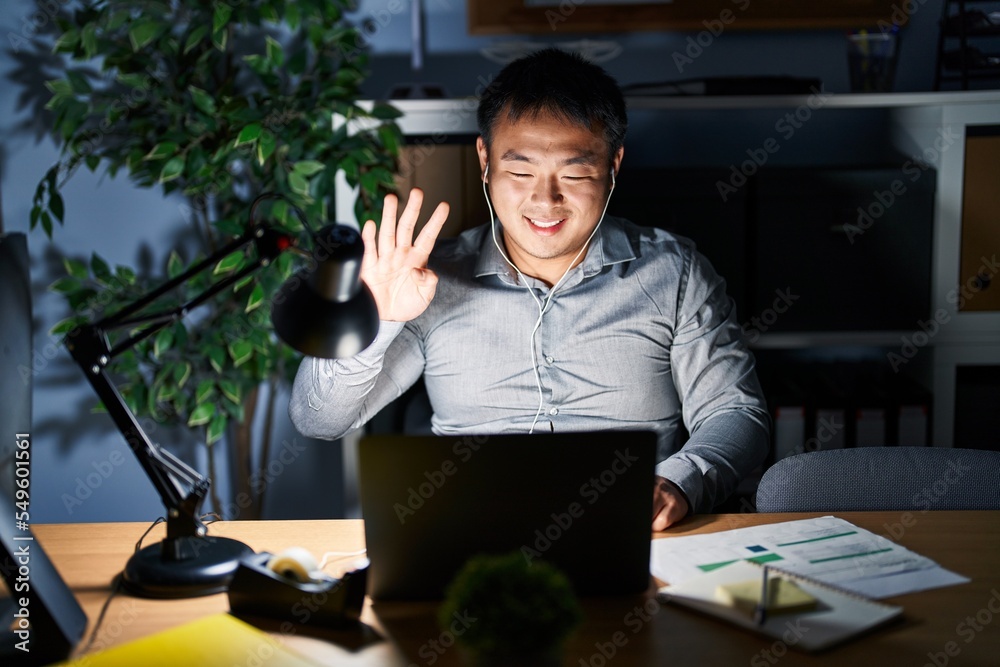 Young chinese man working using computer laptop at night showing and ...
