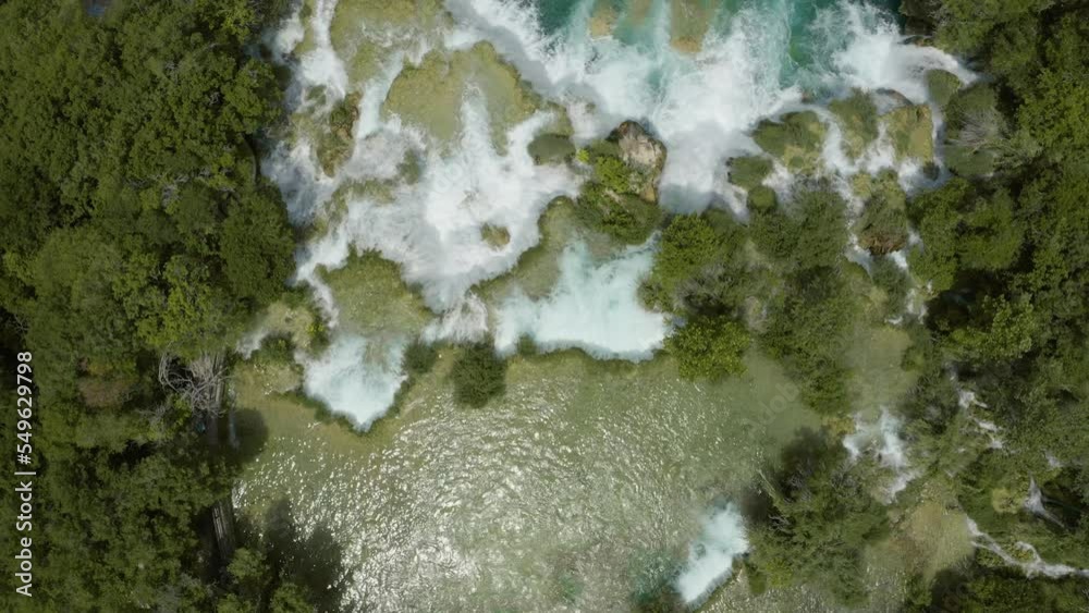 An aerial top down flyover view of a river running down waterfalls and ...