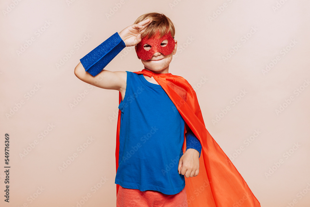 Little superhero boy wears red cape and mask, does military salute with ...