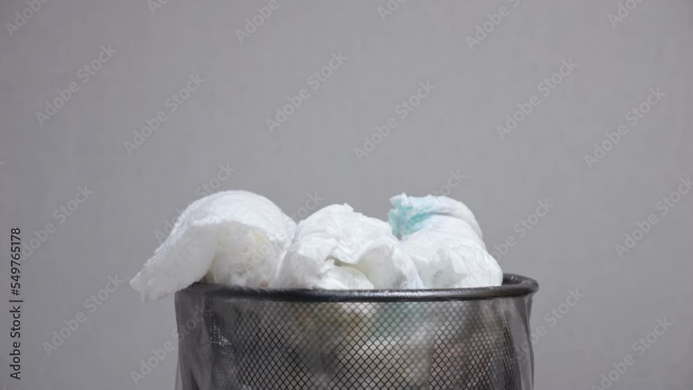 Person throws dirty diapers into loaded bin and changes clean diapers ...