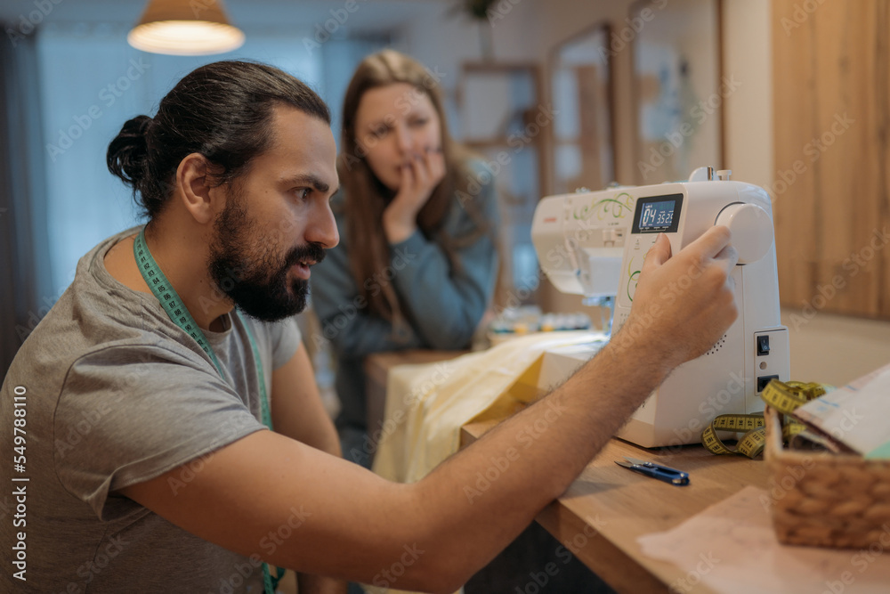 Photo & Art Print A man sews on a sewing machine, a woman explains how ...