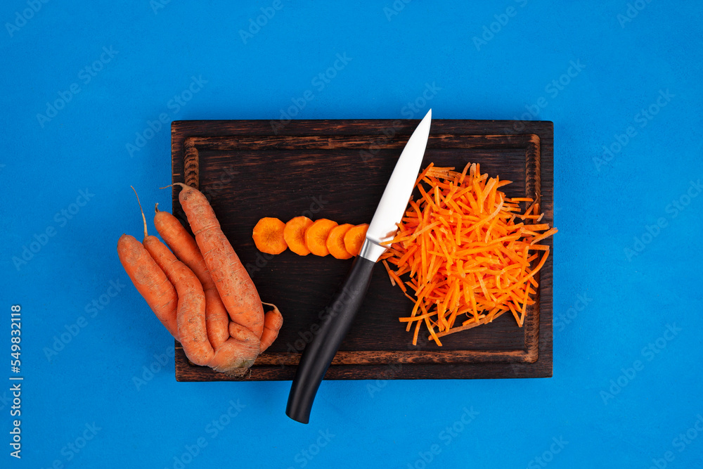 Deformed conjoined carrot and knife on cutting board, top view. Ugly ...