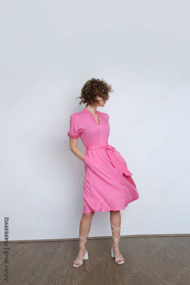 Series of studio photos of young female model in bright pink midi dress ...