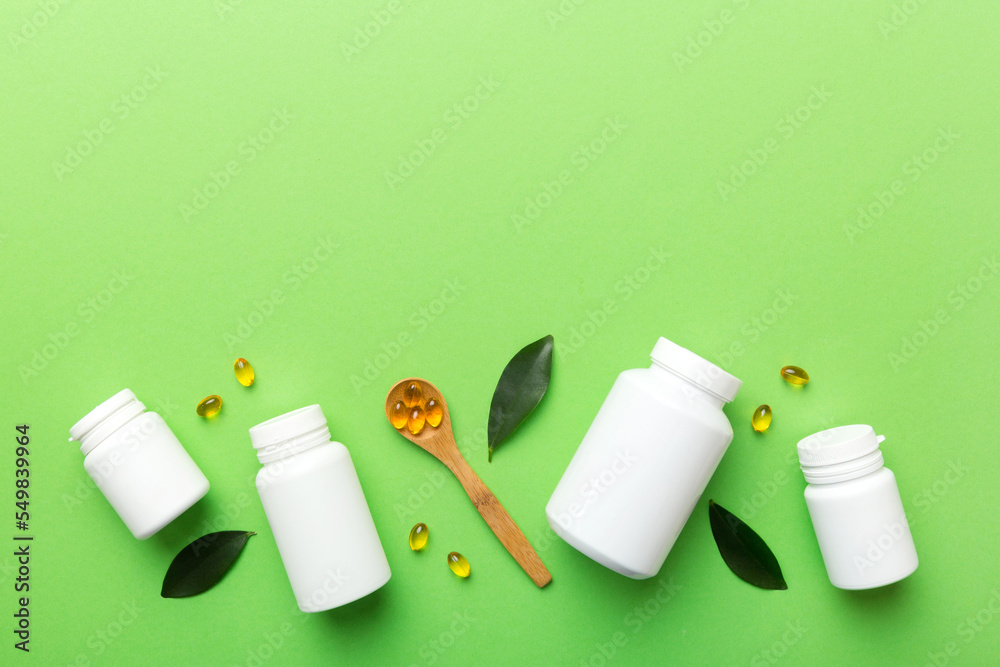 Omega-3 capsules lie in white bottle on a table with green leaves ...