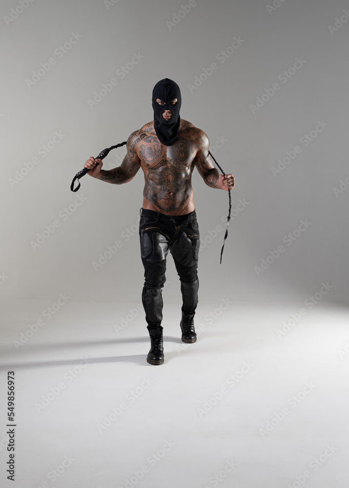 Muscular shirtless young man with whip in a mask.Brutal handsome man ...