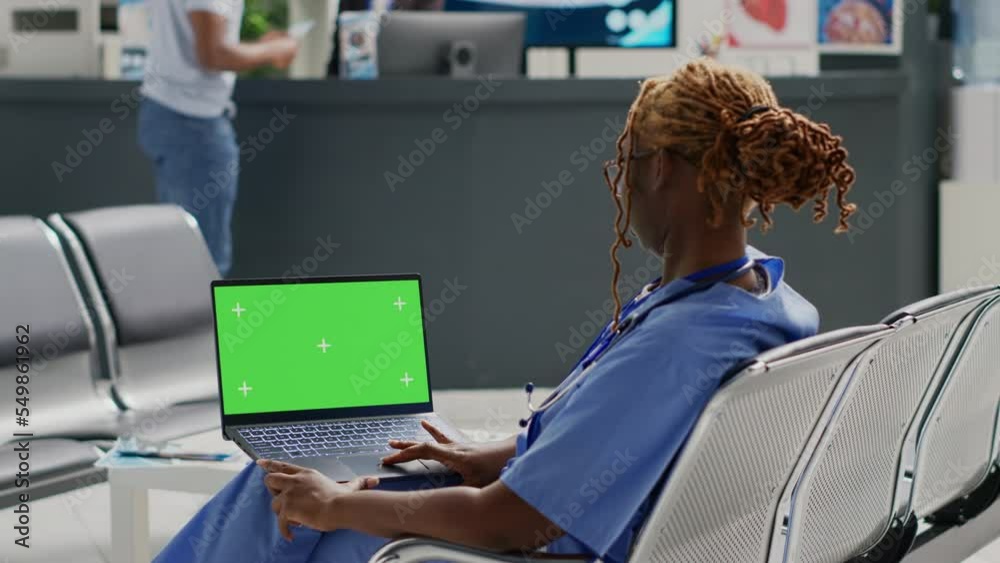 Nurse holding laptop with greenscreen display in waiting room, using ...