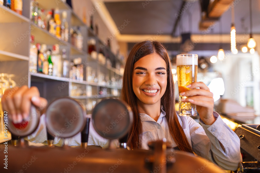 Beautiful smiling female Bartender serving a draft beer at the bar ...