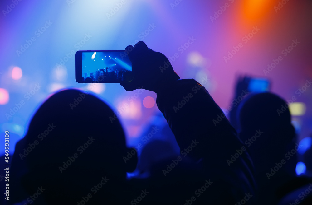 Concert fan filming the show with mobile phone camera. Silhouette of ...