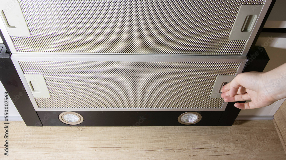 Modern kitchen hood with grease filter for air purification. Replacing ...