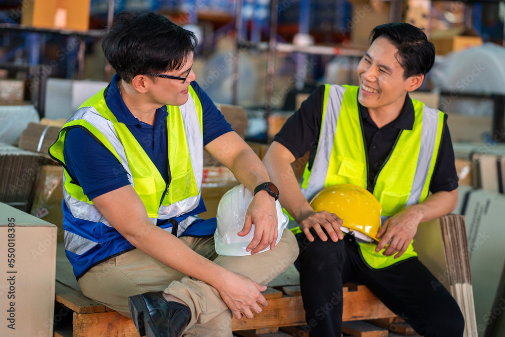Two asian worker men sitting tired during break talking and exchanging ...
