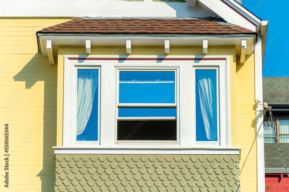 Slightly open window with modern curtains on exterior of beige stucco ...