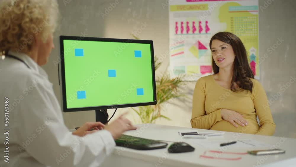 doctor shows a pregnant patient her unborn baby on an ultrasound screen ...