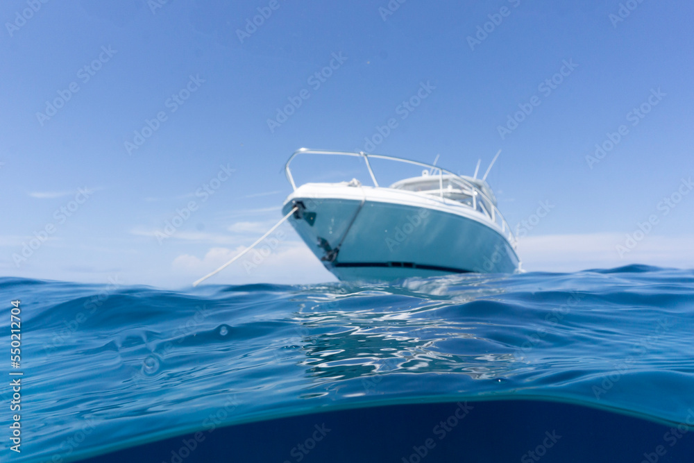 luxury boat sitting on anchor, floating in deep blue water with blue ...
