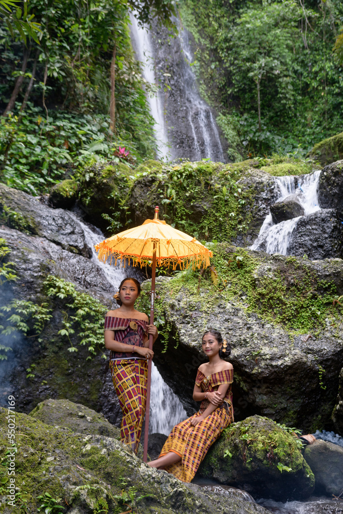 Portrait of two girls in front of a waterfall in a tropical forest ...