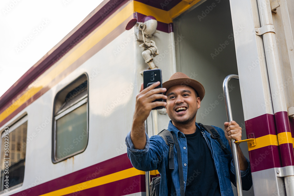 Freedom traveler young asian man hanging handrail on train and taking ...