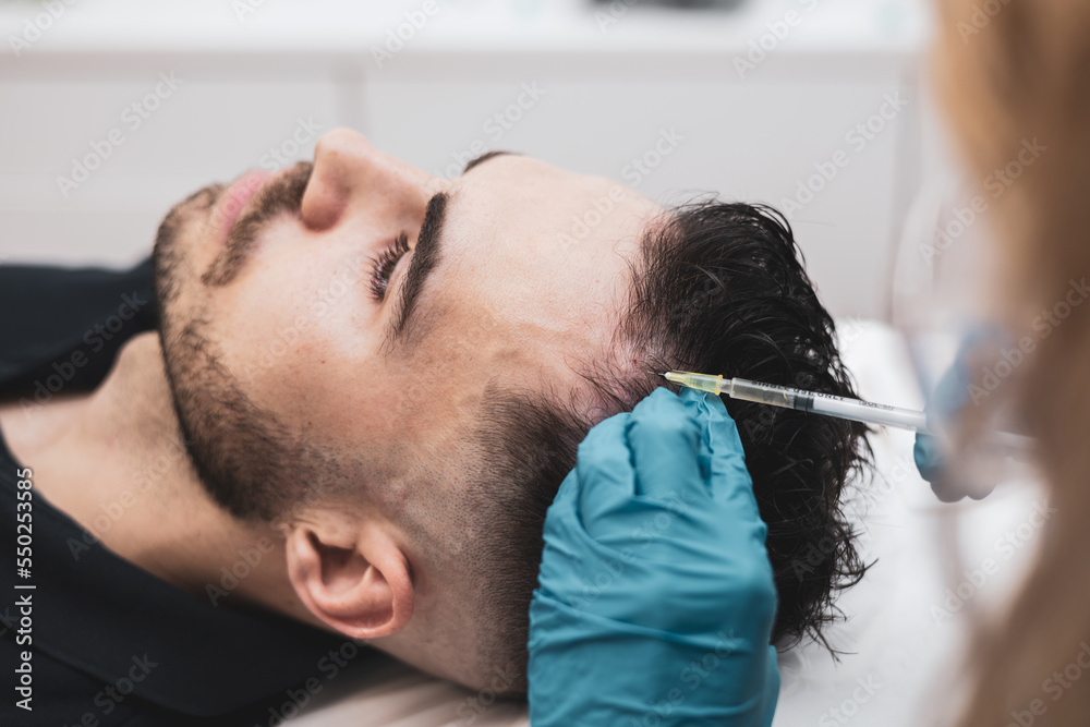 Detail of a young man receiving hair treatment in a beauty salon. Man ...