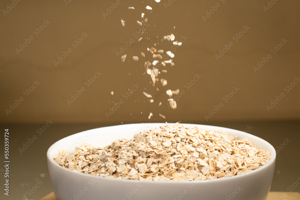 Avena molida siendo vertida en un bol blanco con una cuchara de metal ...