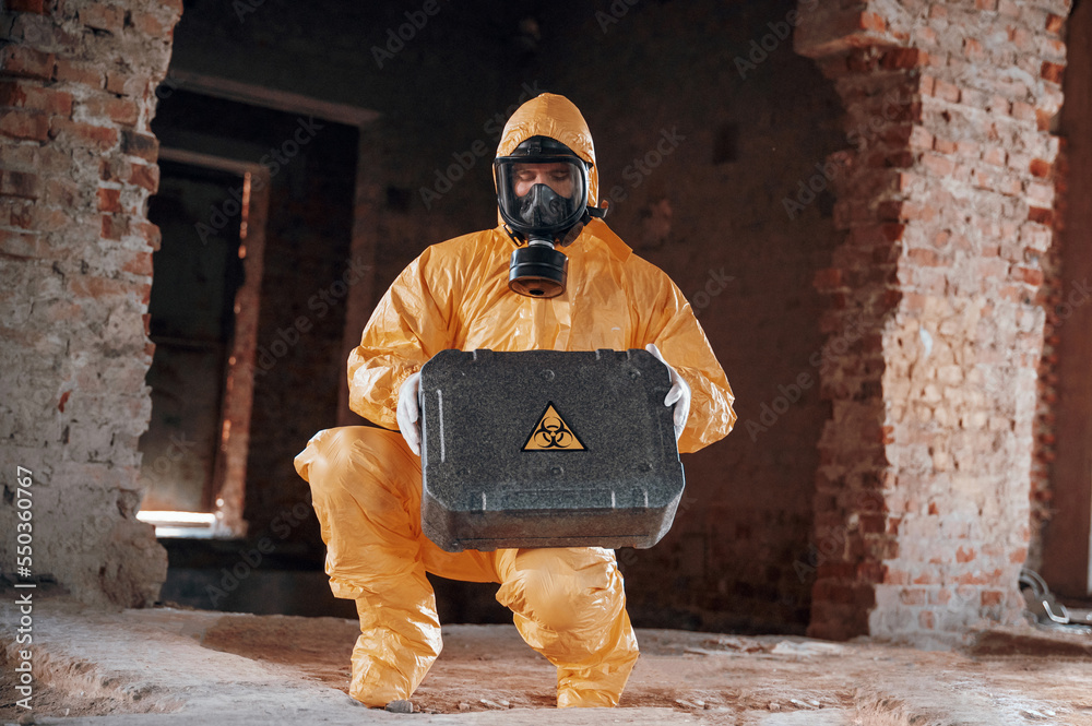 Case with biohazard sign in hands. Man dressed in chemical protection ...