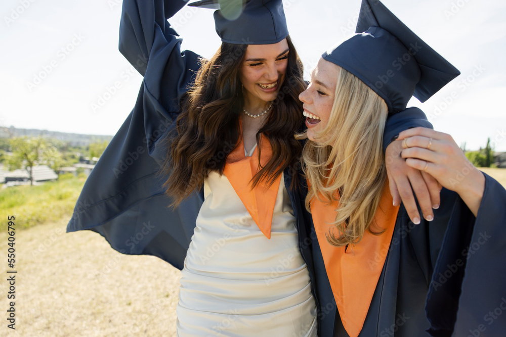 Happy high school girl friend graduates hugging in cap and gown Stock ...