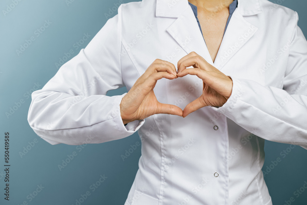 Female doctor in white uniform forms a heart shape with her hands ...