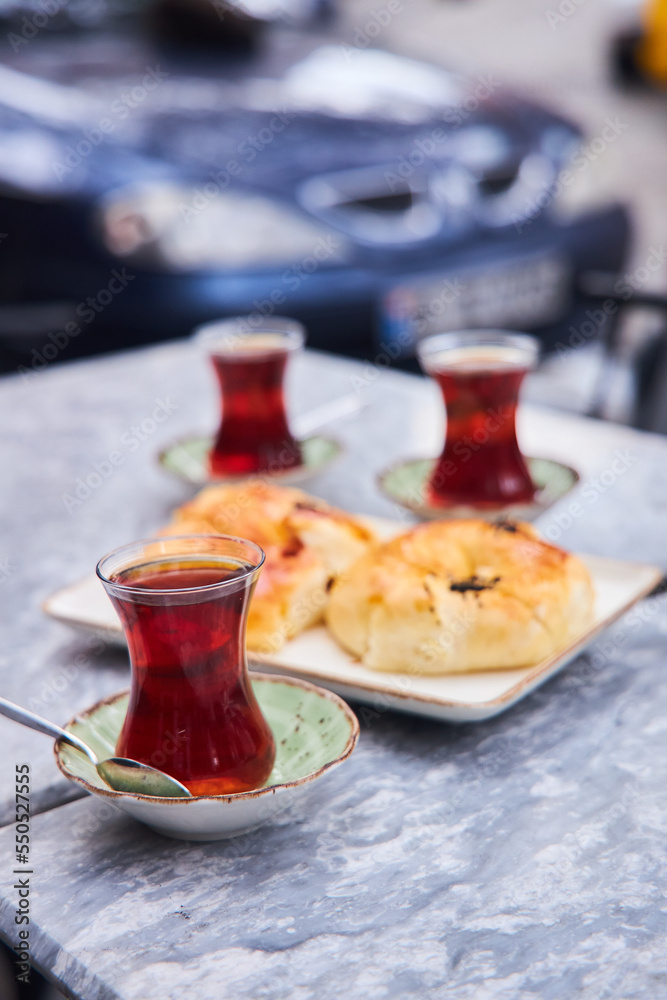 Turkish famous tea in a traditional cup and a fresh bun with black ...