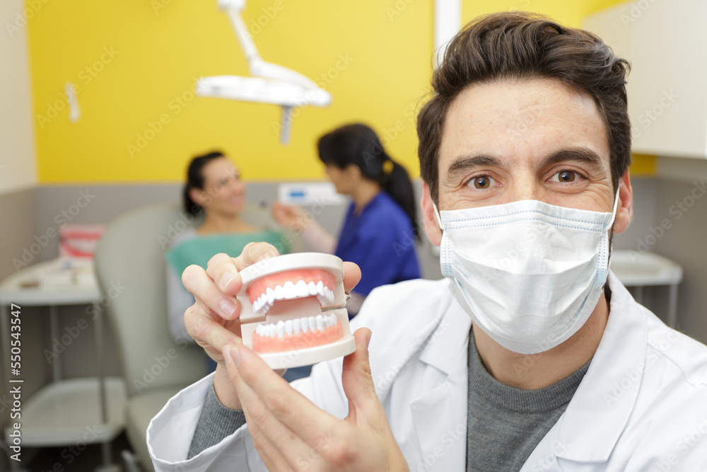 dentist wearing mask showing a set of false teeth Stock Photo | Adobe Stock