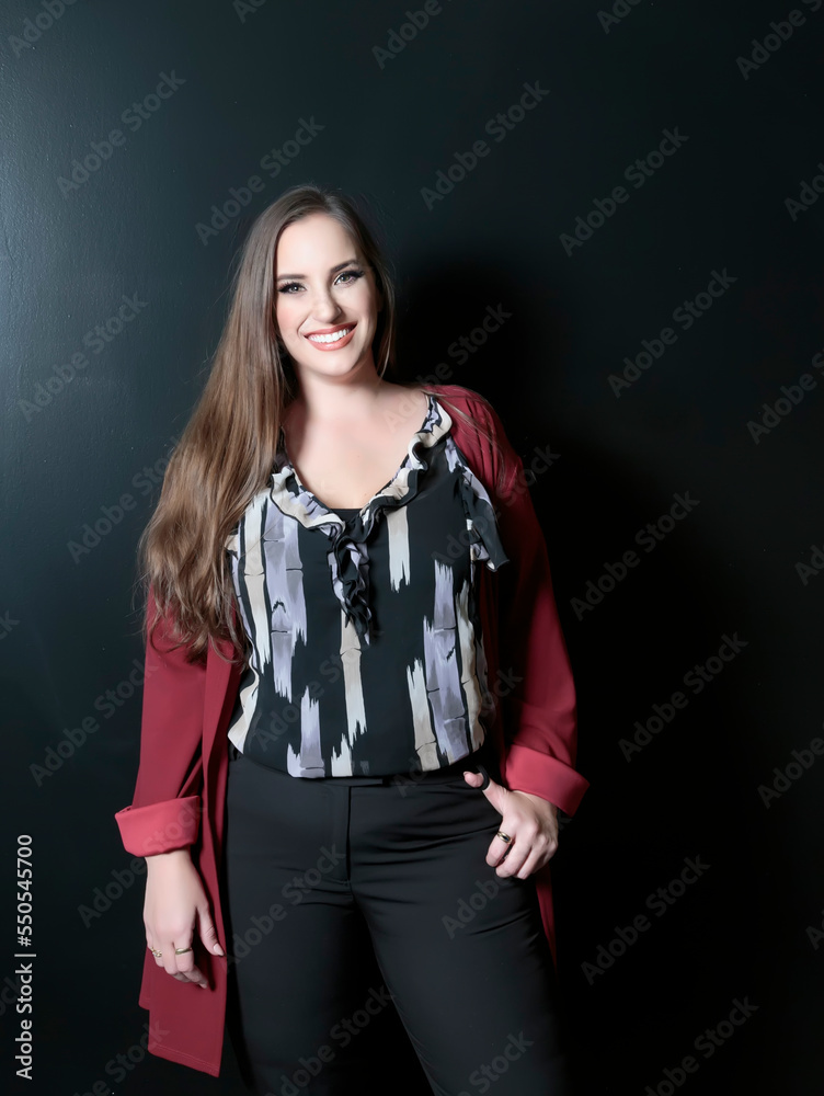 Plus size attractive lady posing and standing against dark backdrop ...