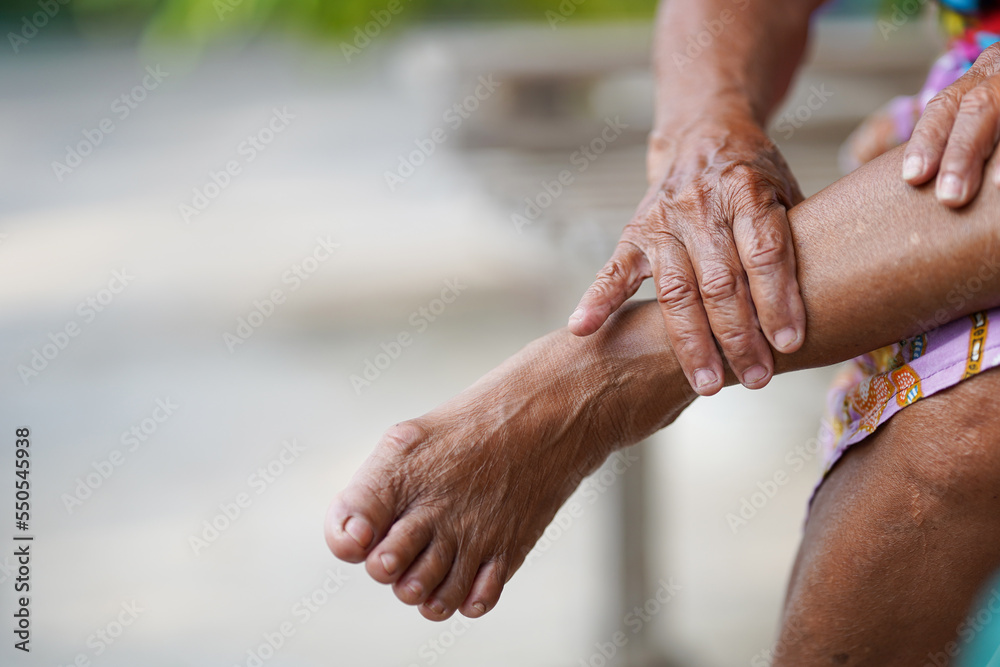 Hand of an elderly woman massaging an ankle with an injury due to ...