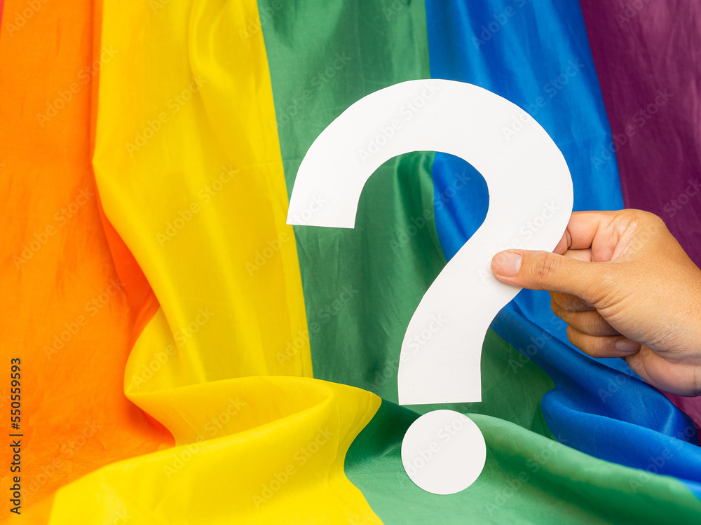 Hand holding of a question mark over the rainbow flag or LGBT flag ...