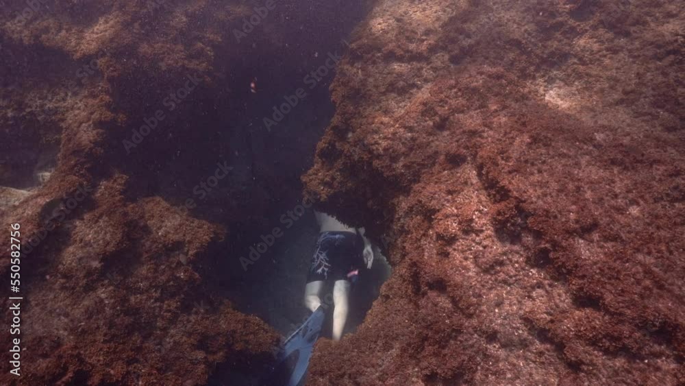 Vídeo do Stock: A young man swims under large rocks of the reef ...