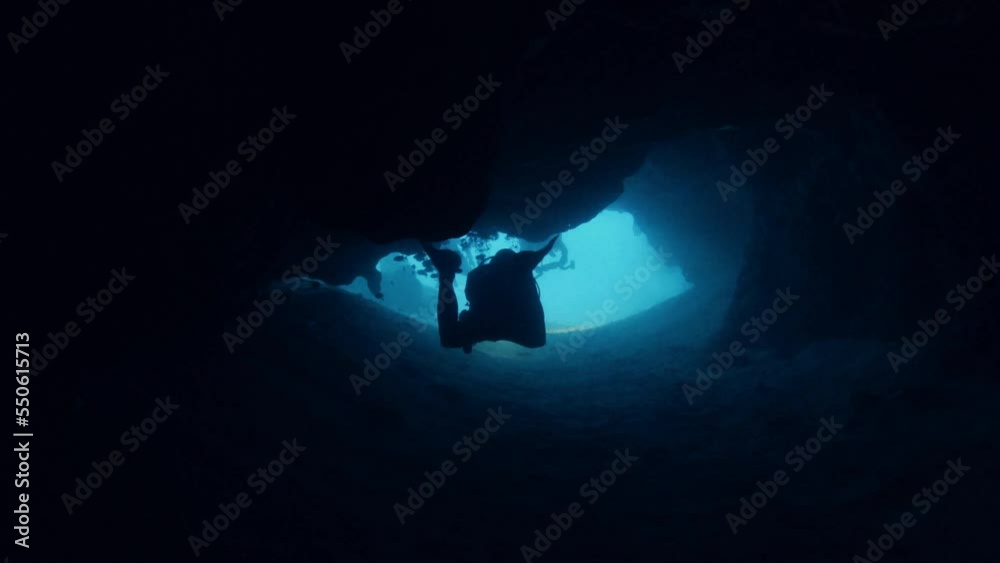 Diver swimming in underwater cave tunnel, back view. Scuba diving in ...
