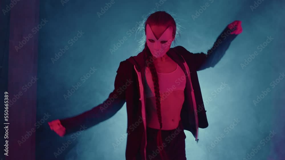 Girl with plait in face mask dancing contemporary against blue smoke ...