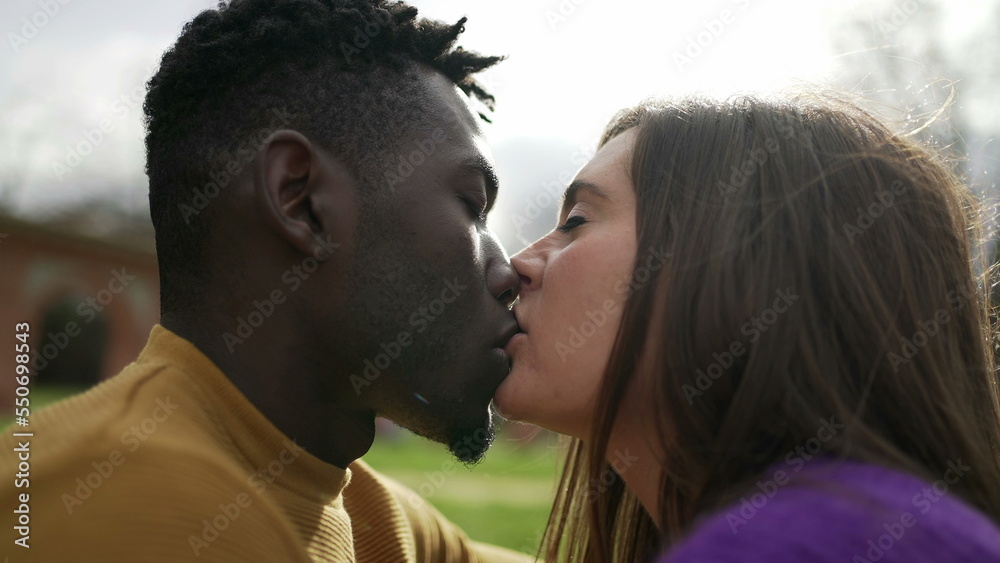 Young millennial couple kissing outside at park. intimate interracial kiss Stock Photo | Adobe Stock