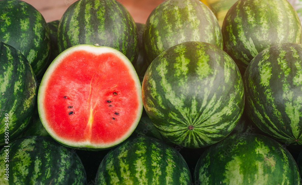 Several large sweet green watermelons and cut watermelons, several ...
