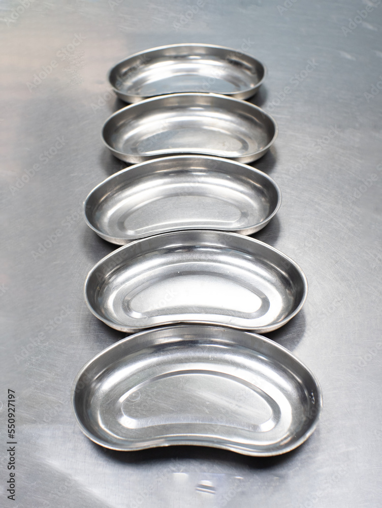 On a metal table there is a row of medical sterile trays. Kidney-shaped ...