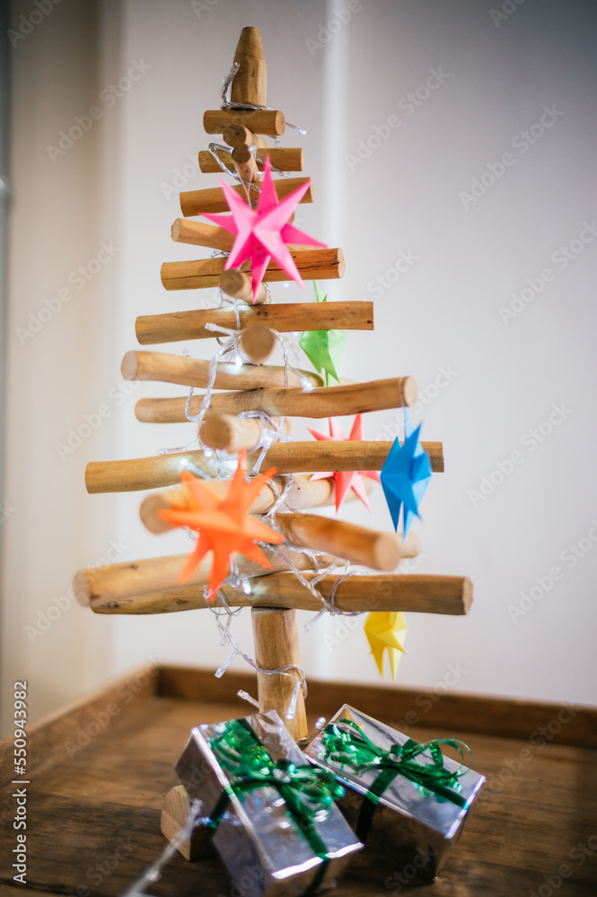 Christmas tree made from wooden sticks, decorated with small lights in ...
