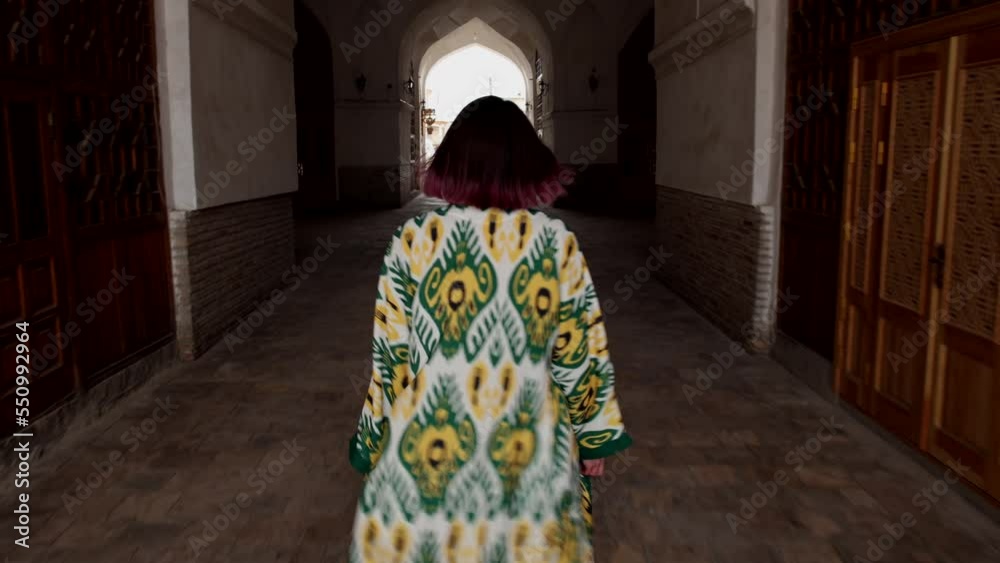 4K. Overall plan. An oriental girl in a traditional Uzbek robe walks ...