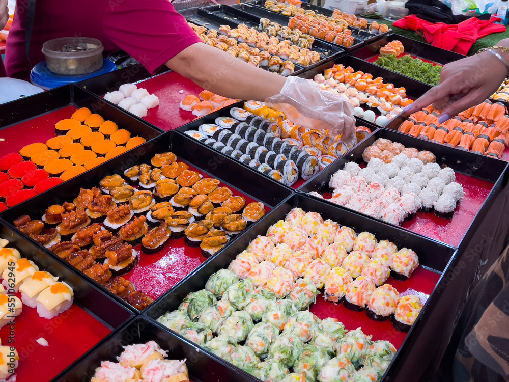 Arm of street market vendor and customer on sushi stall. Traditional ...