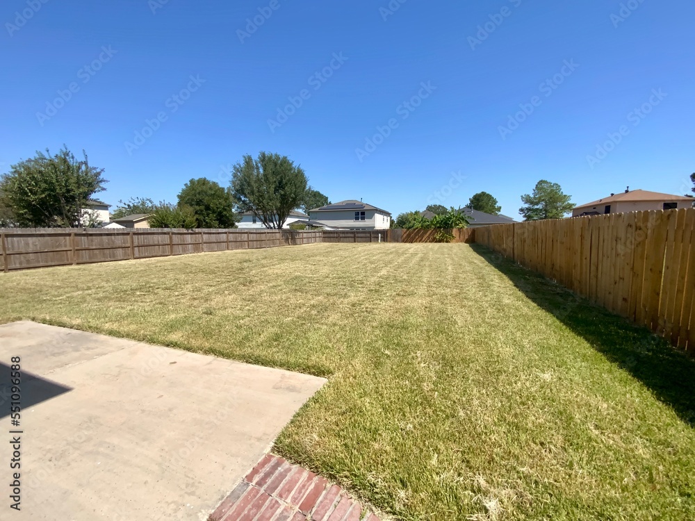Large suburban backyard with a rustic wood fence, trimmed grass, and a ...