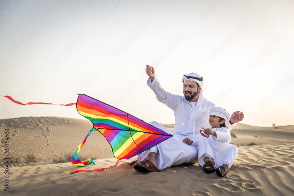 Playful arab man and his son wering traditional middle eastern emirate ...