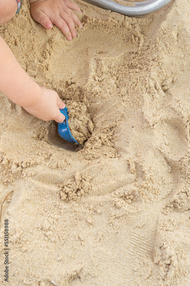 child digging hole in clean beach sand during sunny day with family ...