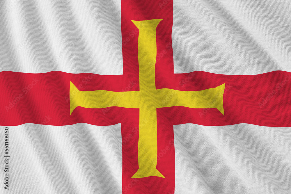 Guernsey flag with big folds waving close up under the studio light ...