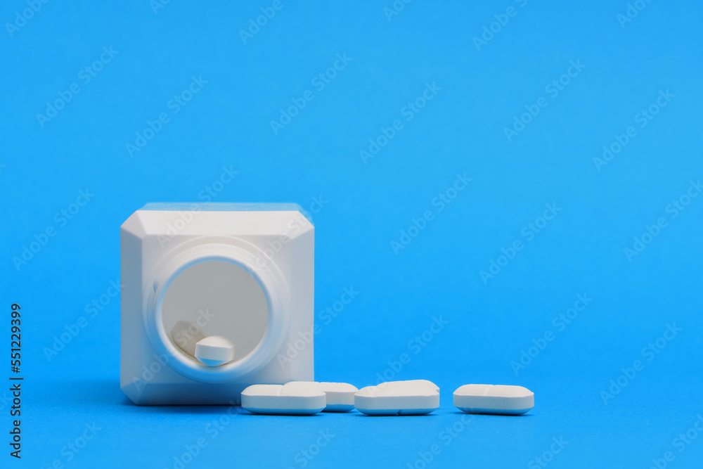 A white, open prescription medication container with some tablets out ...