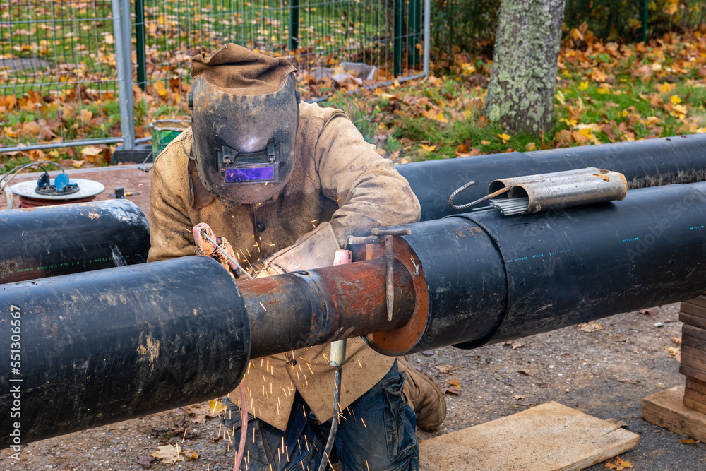 Soudure des tuyaux d'un réseau de chaleur par un soudeur. Chauffage ...
