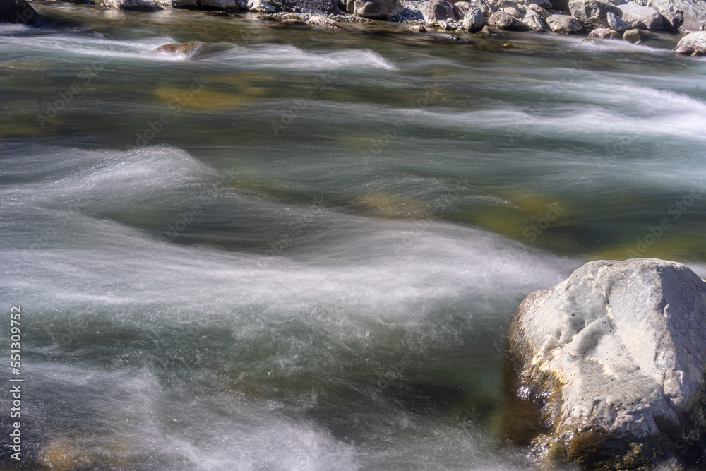In the long exposure picture, the water of the river appears to be ...