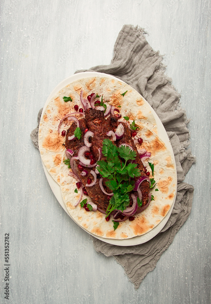 Lula kebab, on lavash, with red onion, pomegranate, and sumac, top view ...