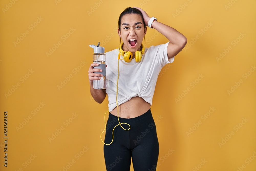 Young south asian woman wearing sportswear drinking water crazy and ...