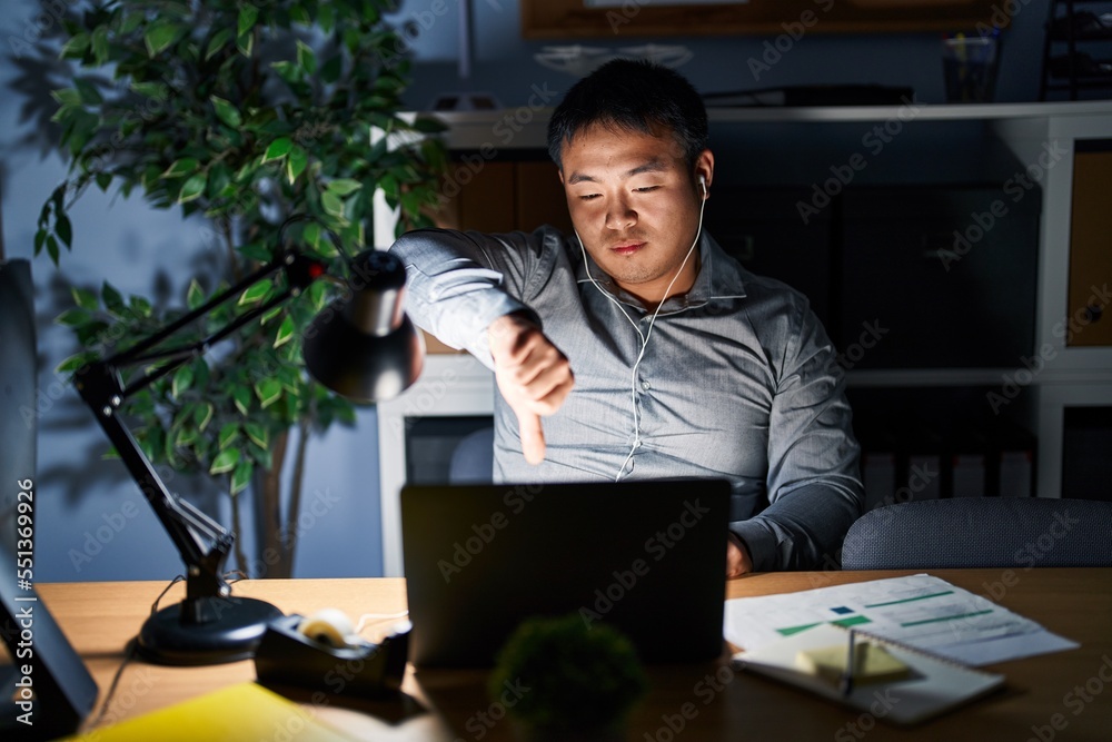 Young chinese man working using computer laptop at night looking ...