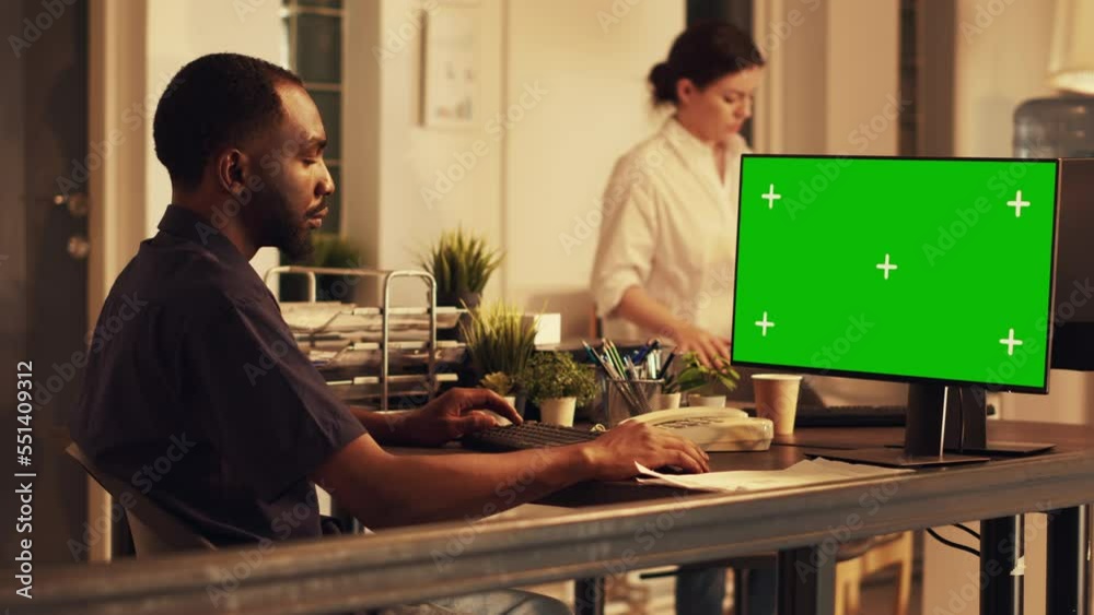 Male manager looking at computer with greenscreen display, working with ...