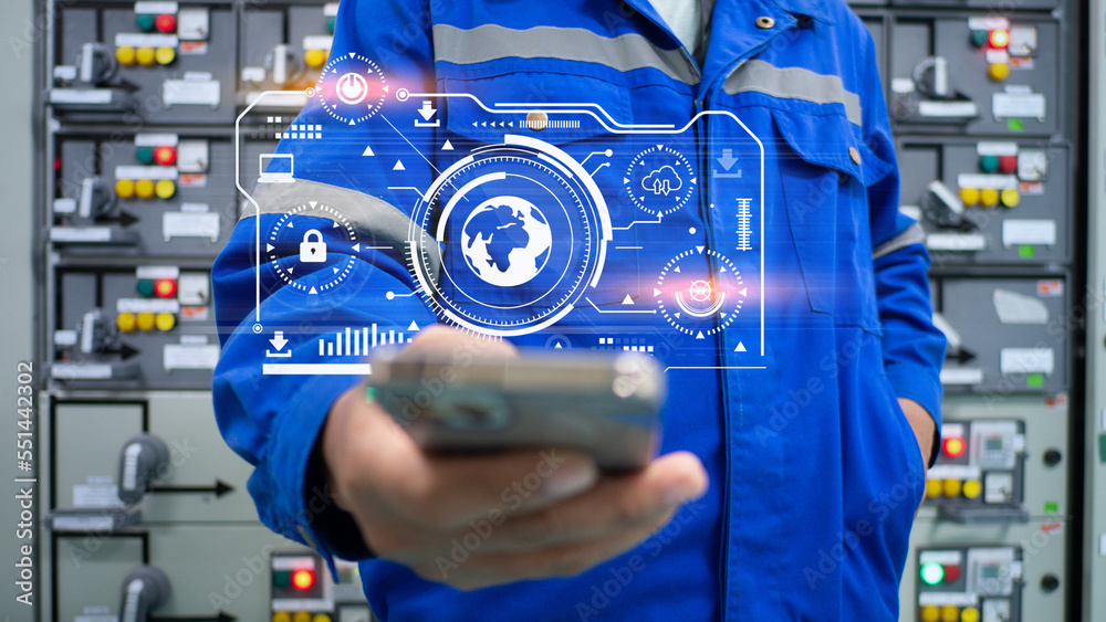 Engineer in electrical control room of industrial plant is using mobile ...
